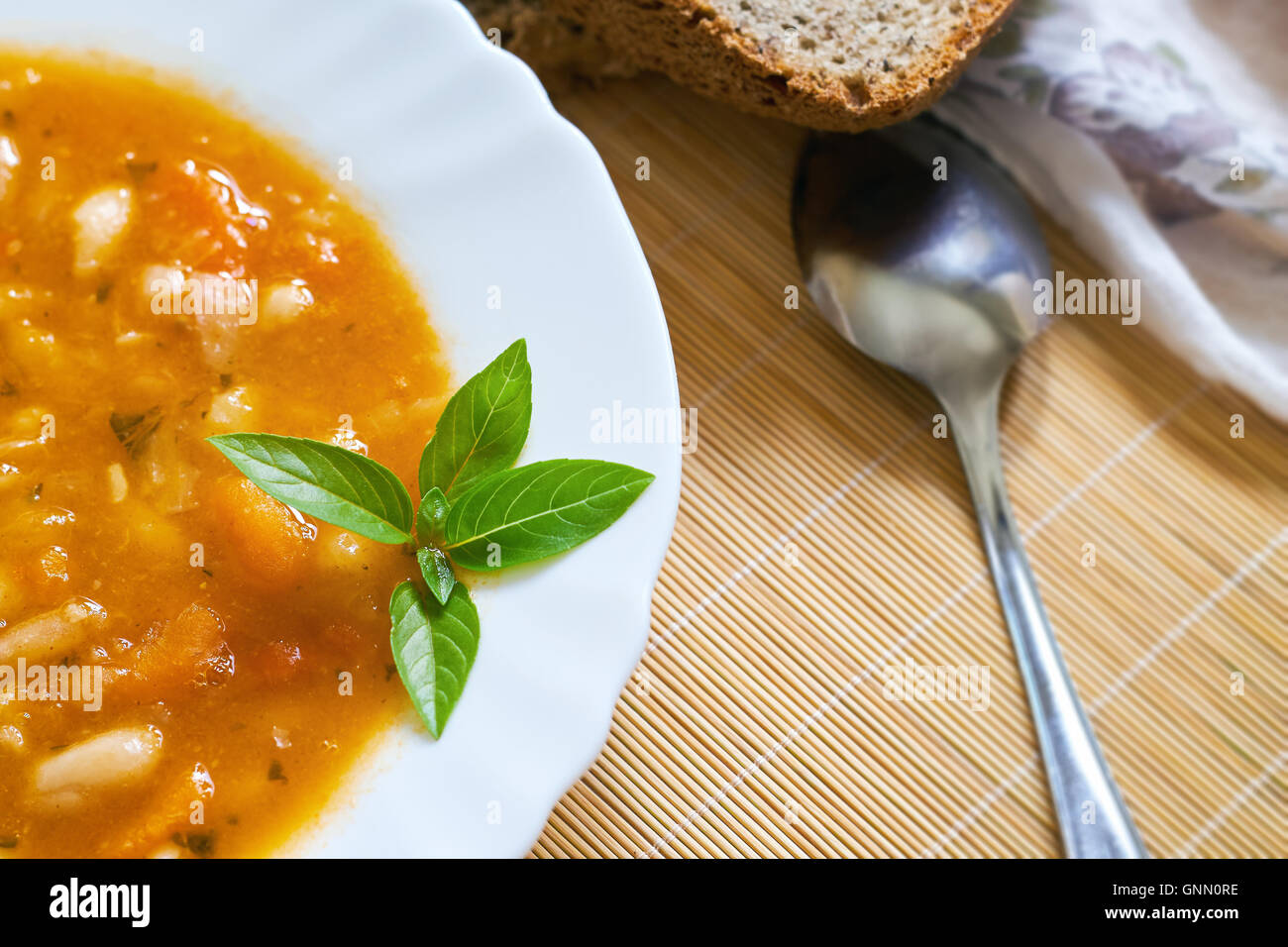Cooked beans served in white plate with basil leaves and whole wheat ...