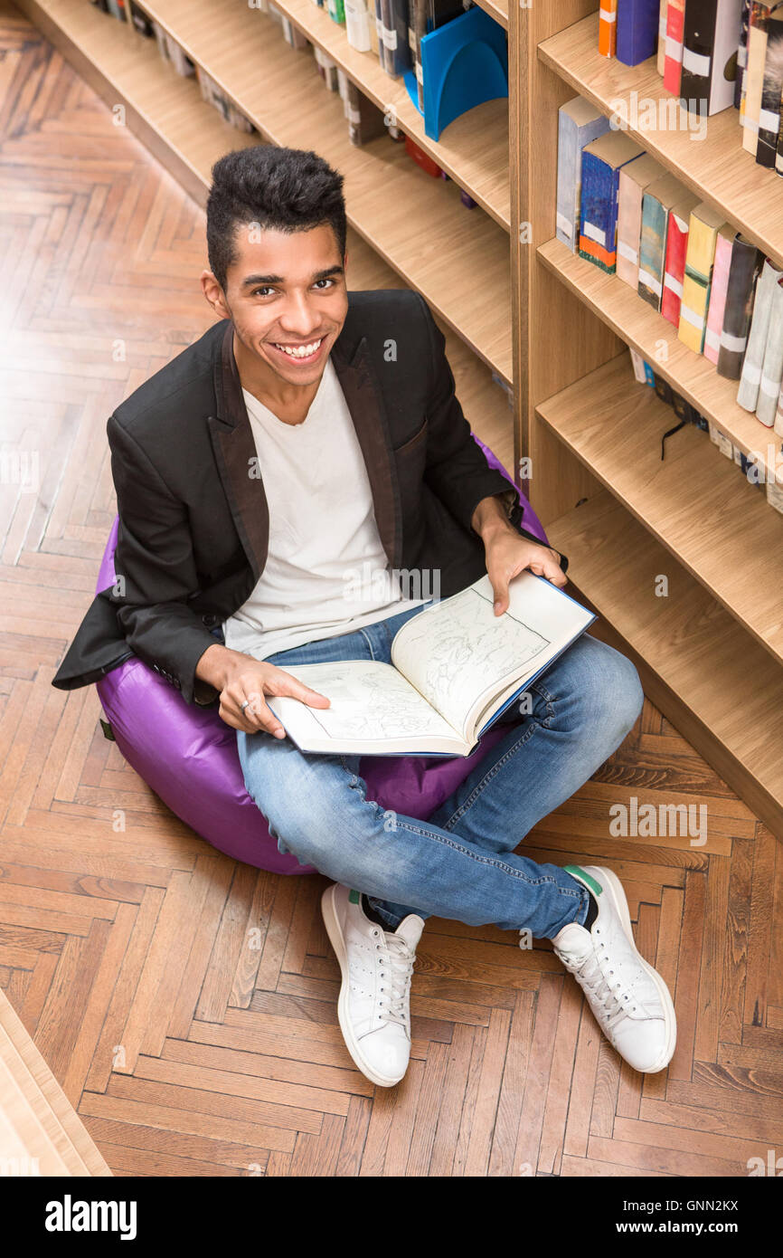 Handsome man reading book in library Stock Photo - Alamy