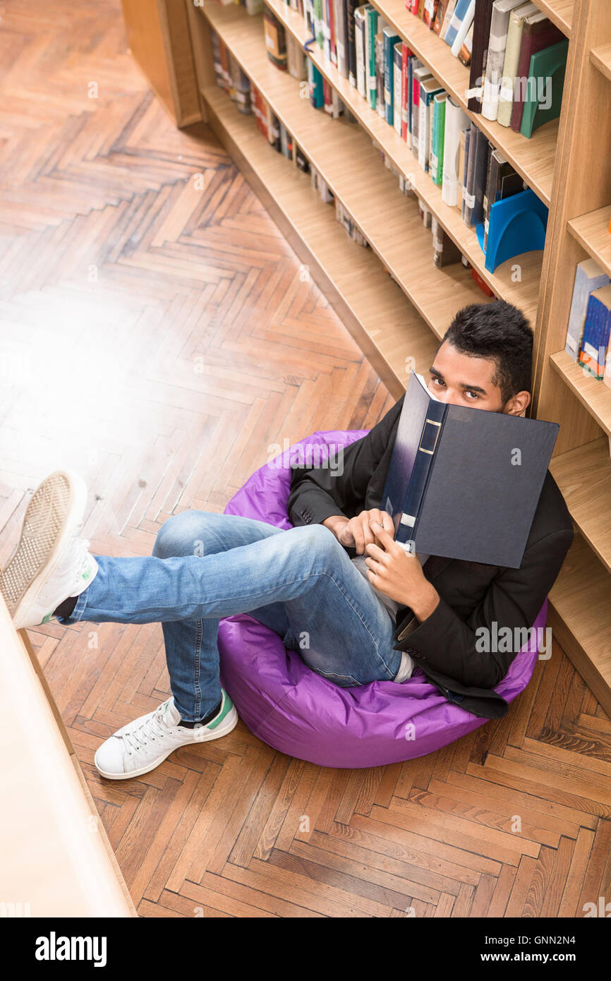 Handsome man reading book in library Stock Photo - Alamy