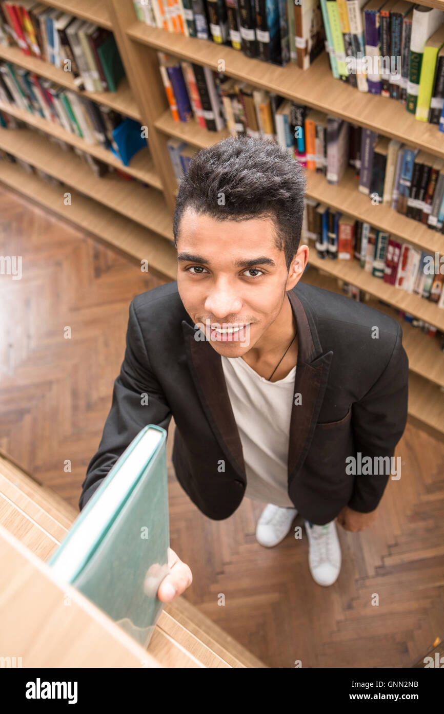 Handsome man taking a book in library Stock Photo - Alamy