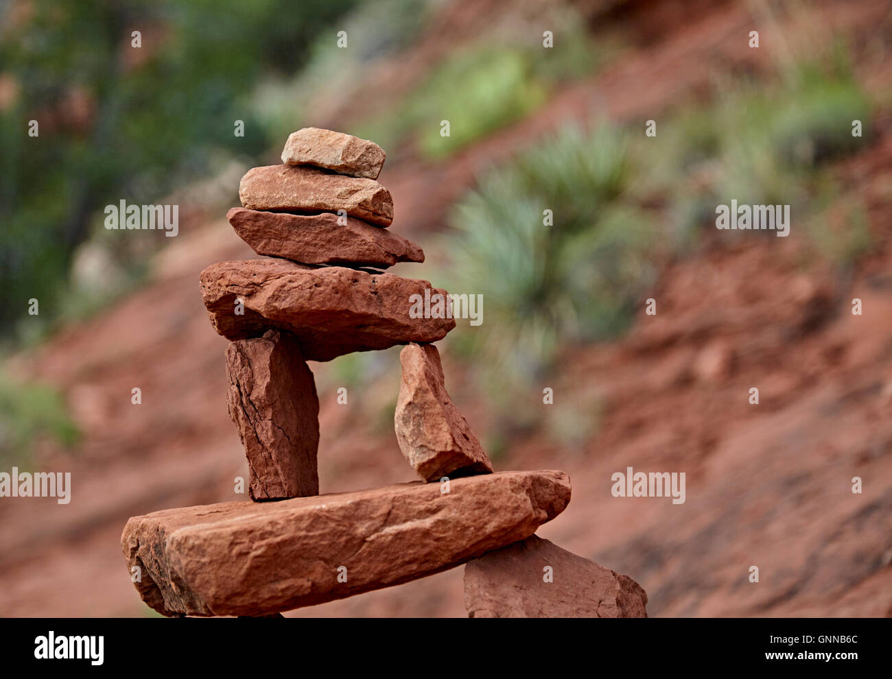Stacked red rocks balanced on side of mountain Stock Photo - Alamy