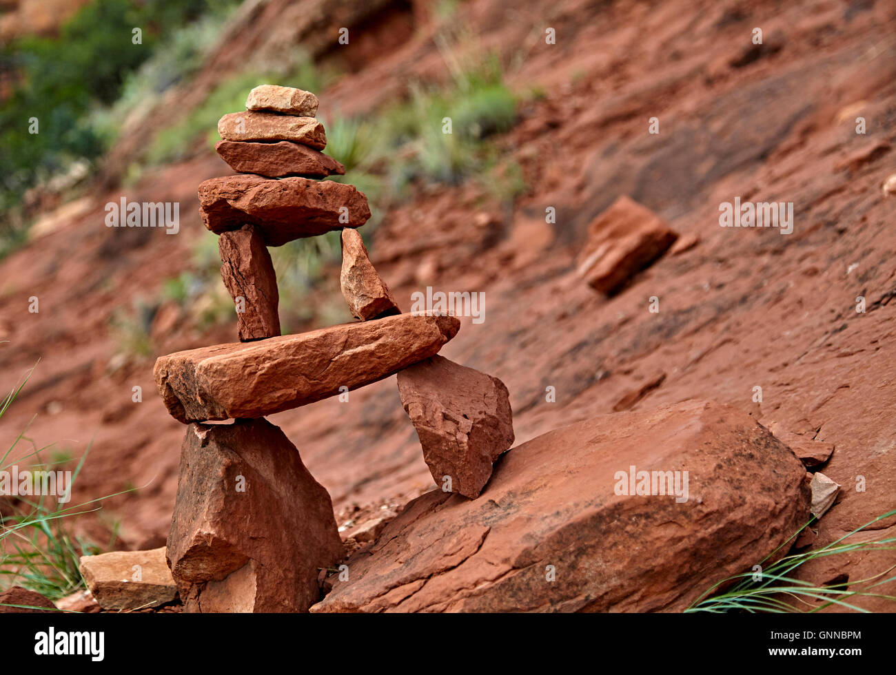 Stacked red rocks balanced on side of mountain Stock Photo - Alamy