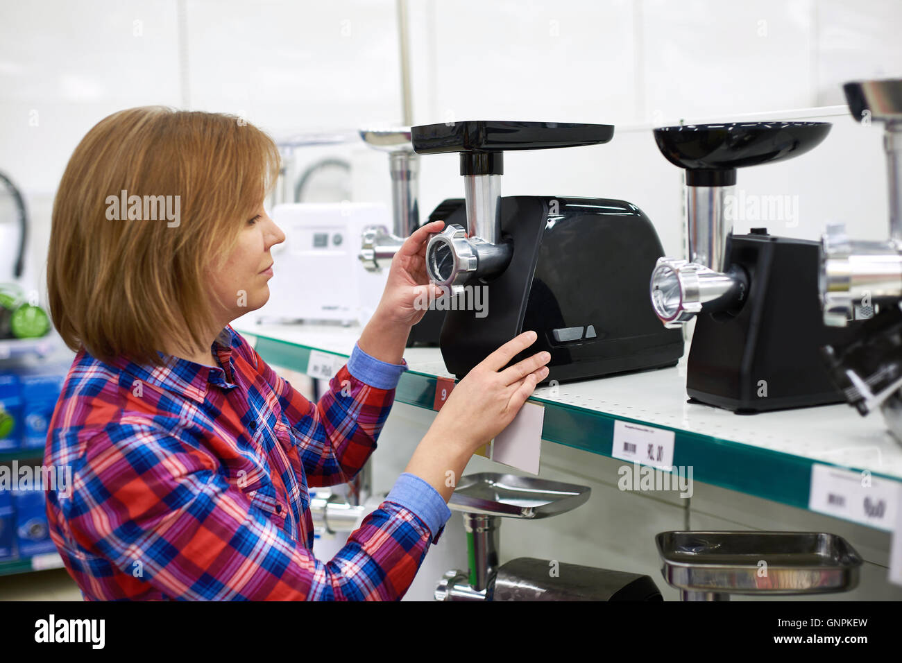 Woman housewife chooses the electric meat grinder in the shop Stock ...