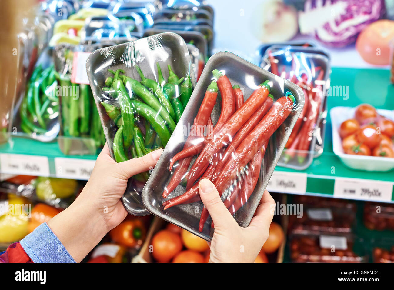 Buyer selects the chili peppers in the store Stock Photo - Alamy