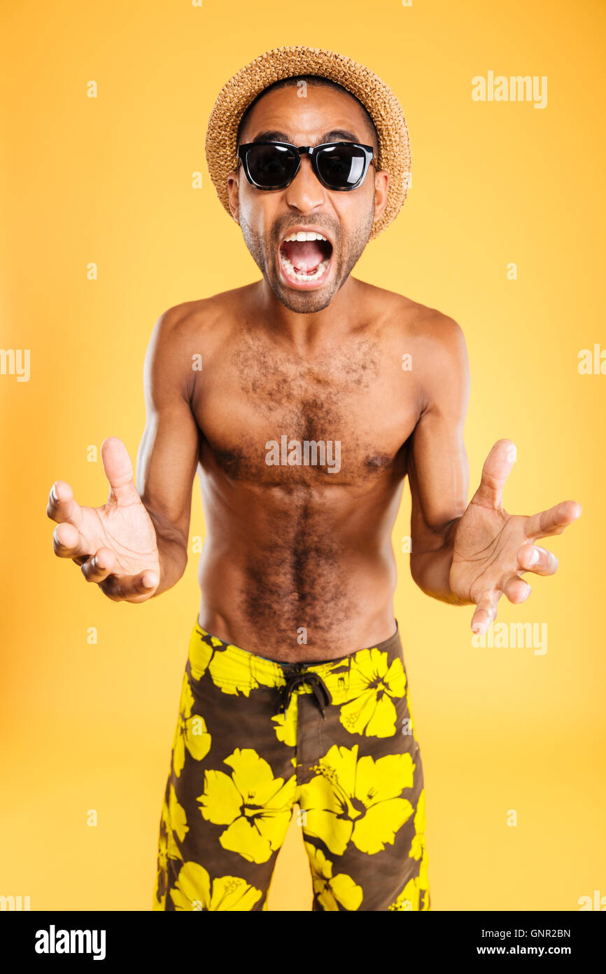 Angry mad african man in swimwear and sunglasses standing and shouting ...