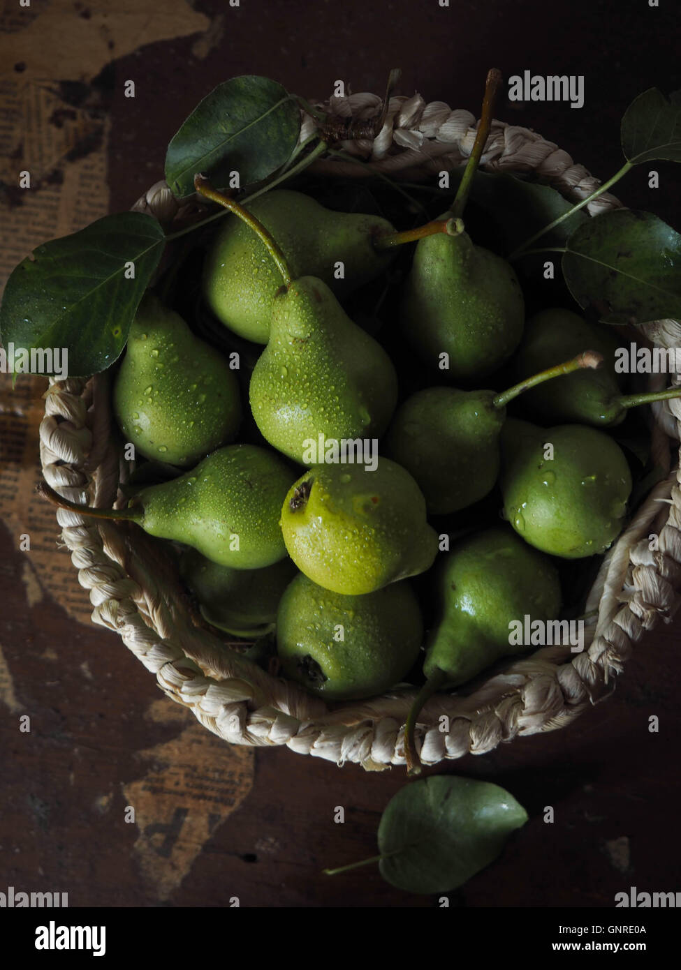Green pears with leaves in wicker basket on a wood background Stock ...