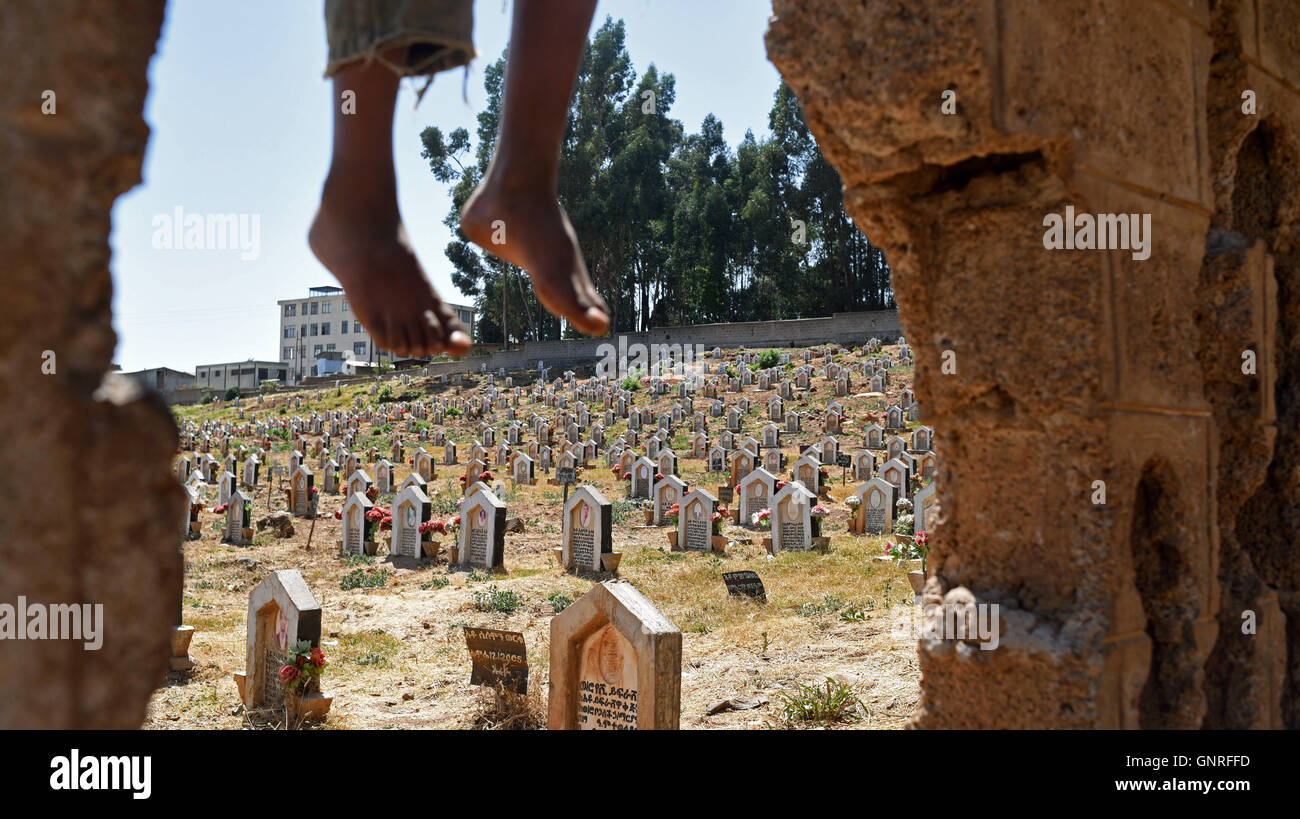 A young boy plays on a wall overlooking a cemetery in Addis Ababa ...