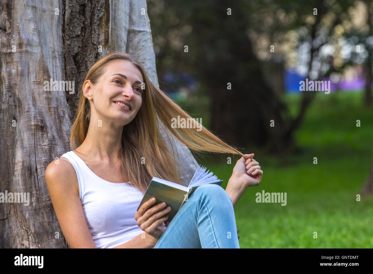 Young woman sitting on the grass and reading book outdoor Stock Photo ...