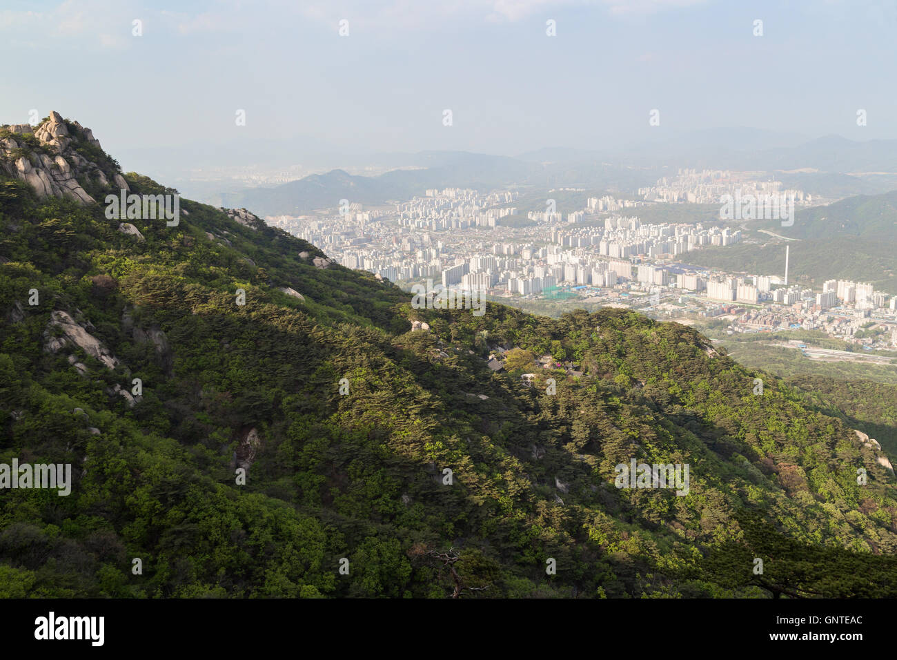 View of the city far away from above, mountain and lush forest at the ...