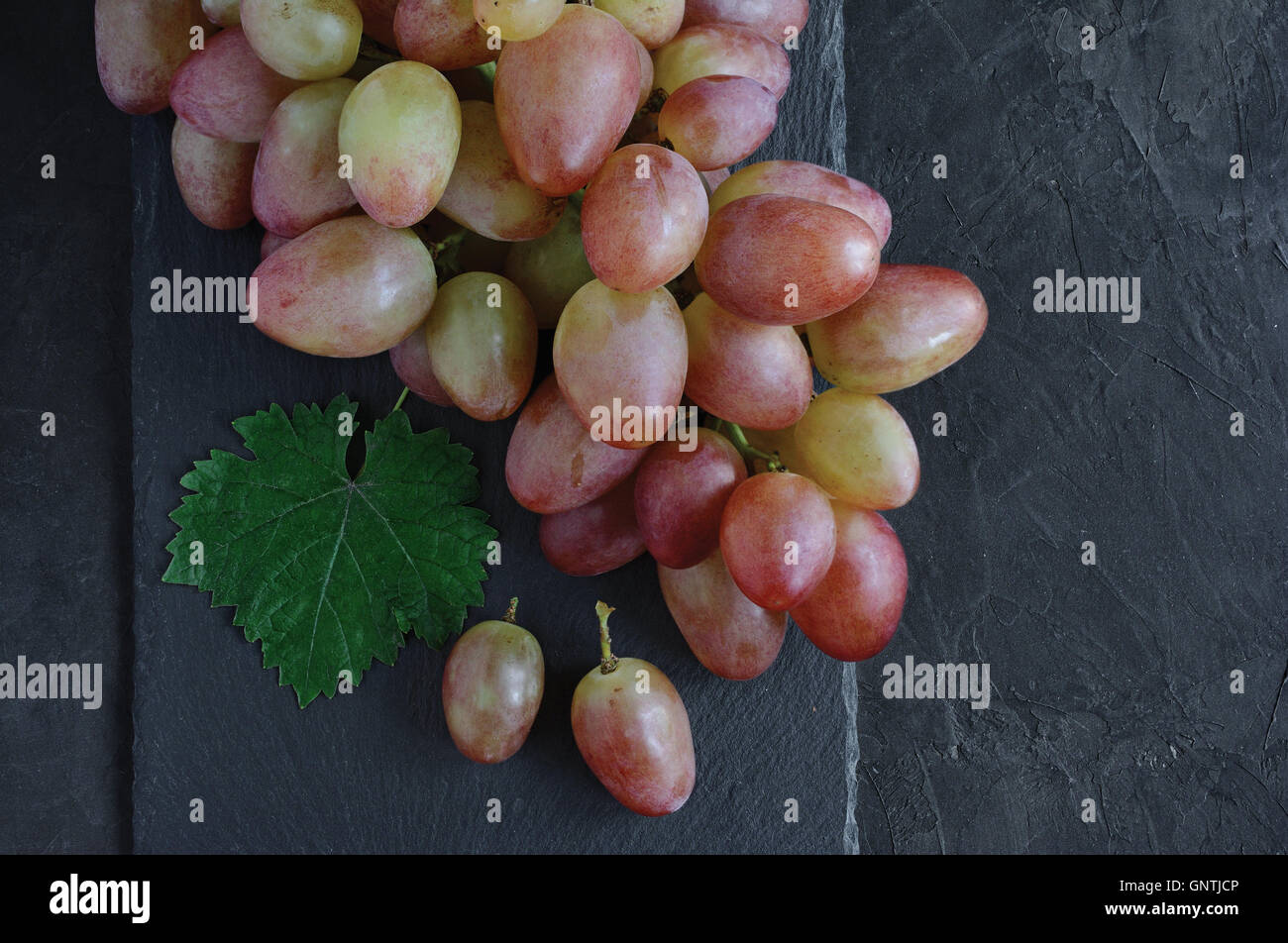 Bunch of grapes on a black slate background Stock Photo - Alamy