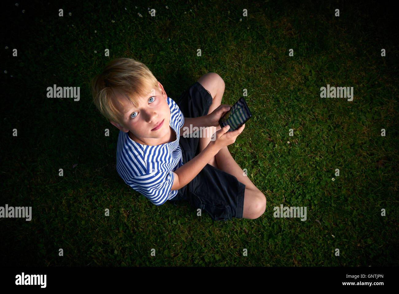 Child young boy with mobile phone outdoor. Child looking at the screen ...