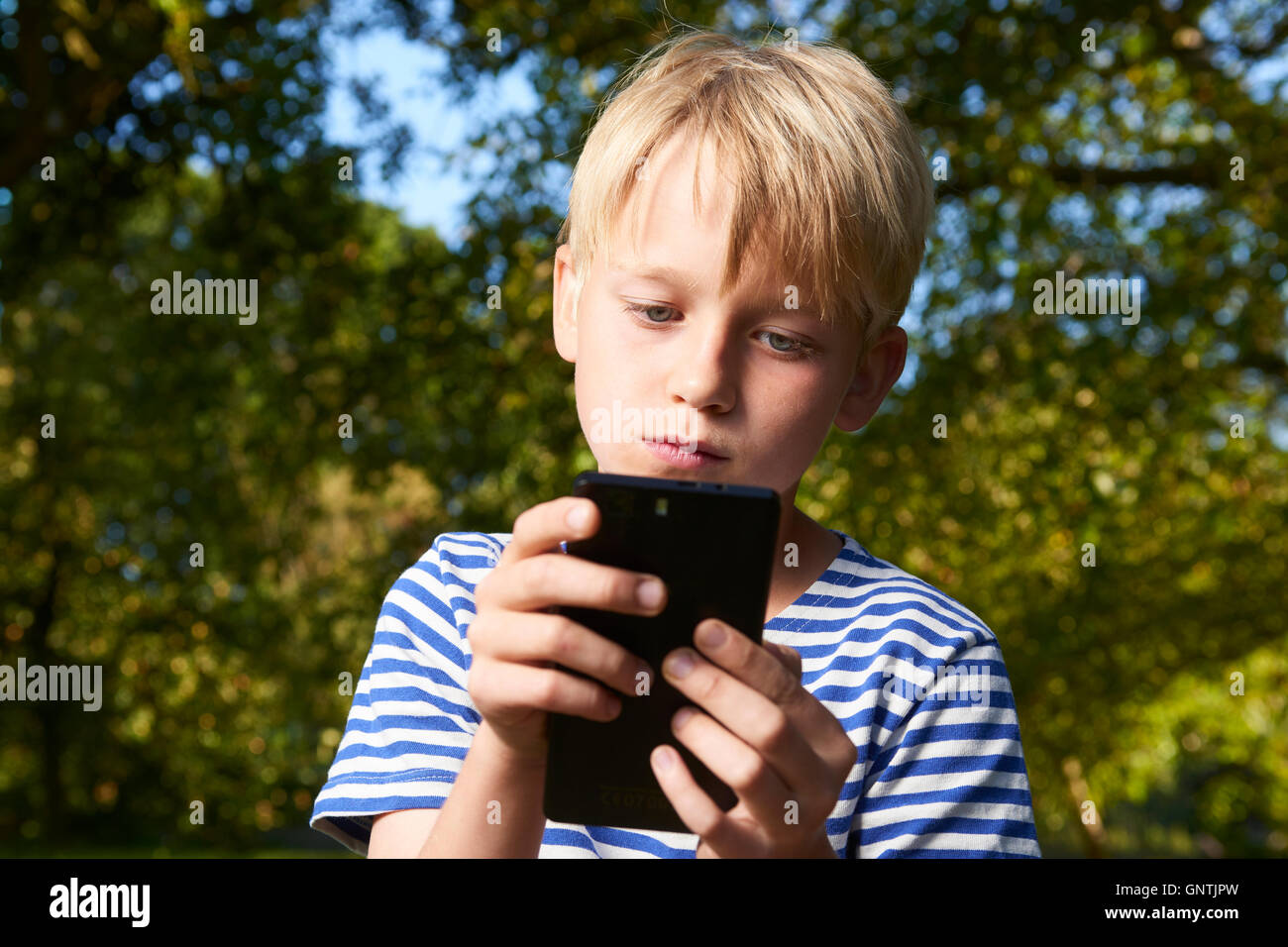 Child young boy with mobile phone outdoor. Child looking at the screen ...