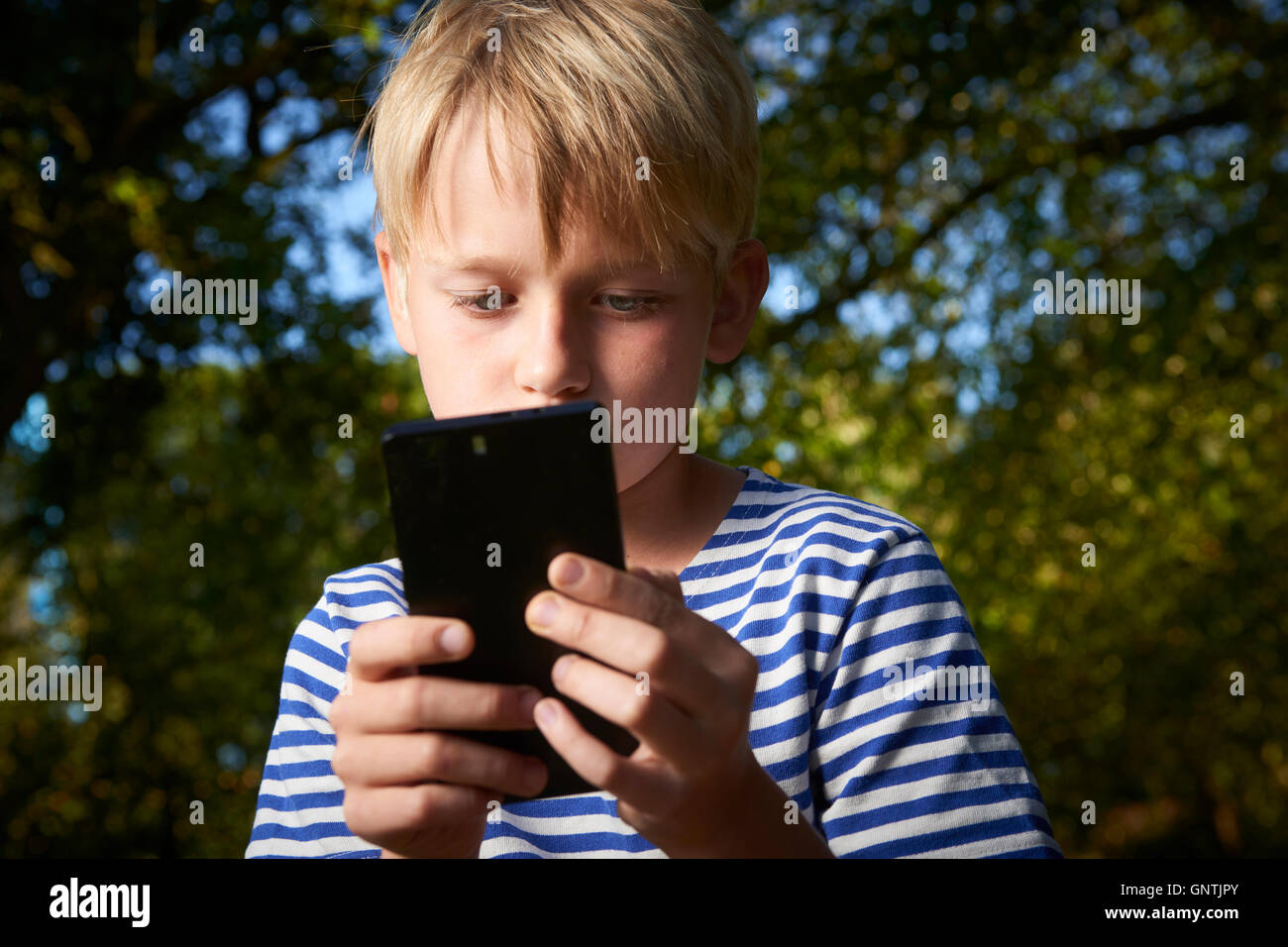Child young boy with mobile phone outdoor. Child looking at the screen ...