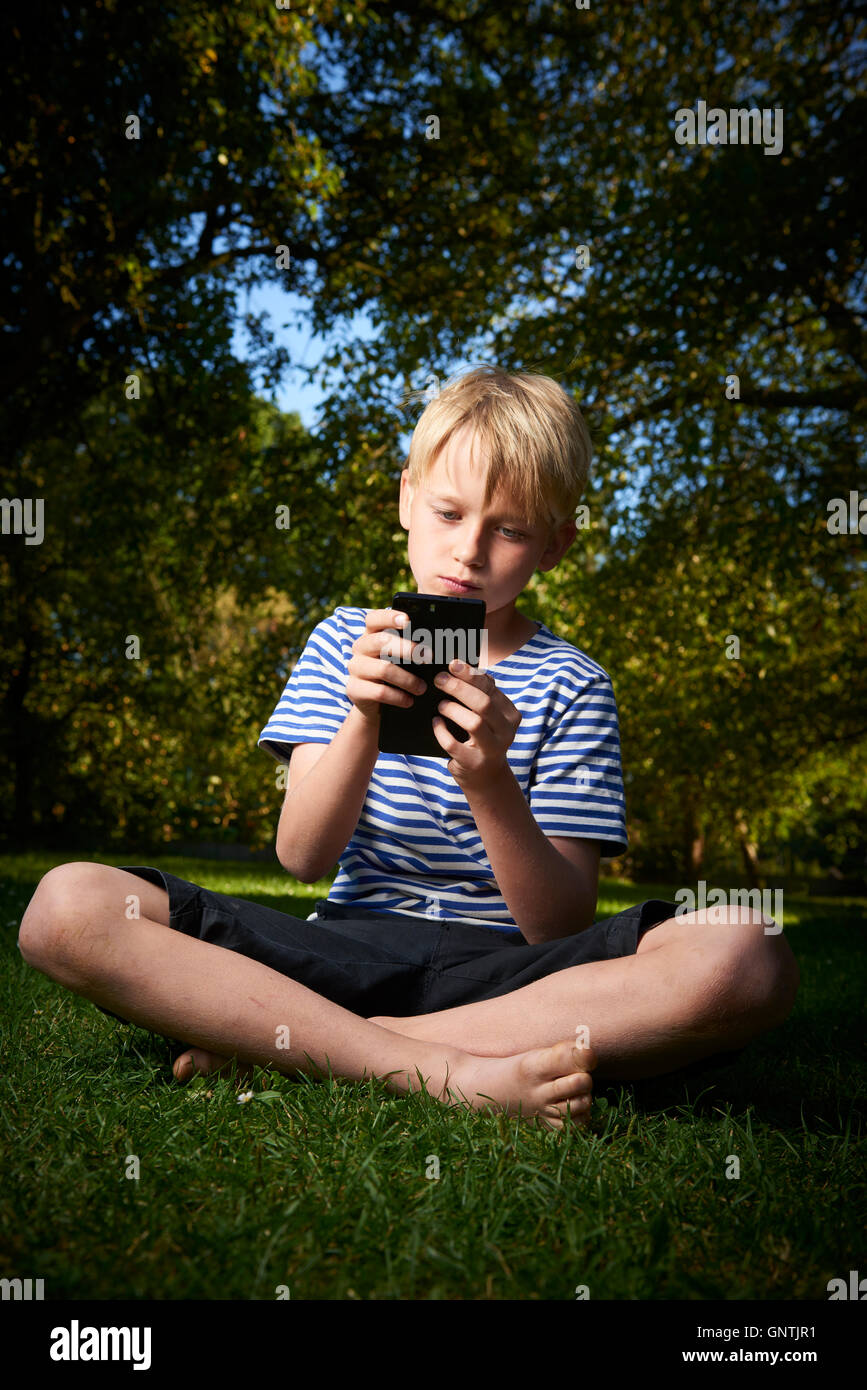 Child young boy with mobile phone outdoor. Child looking at the screen ...