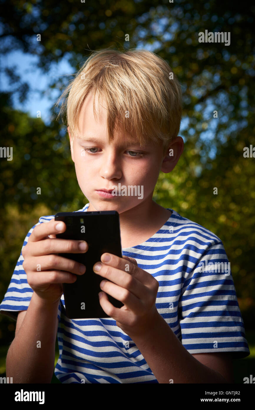 Child young boy with mobile phone outdoor. Child looking at the screen ...