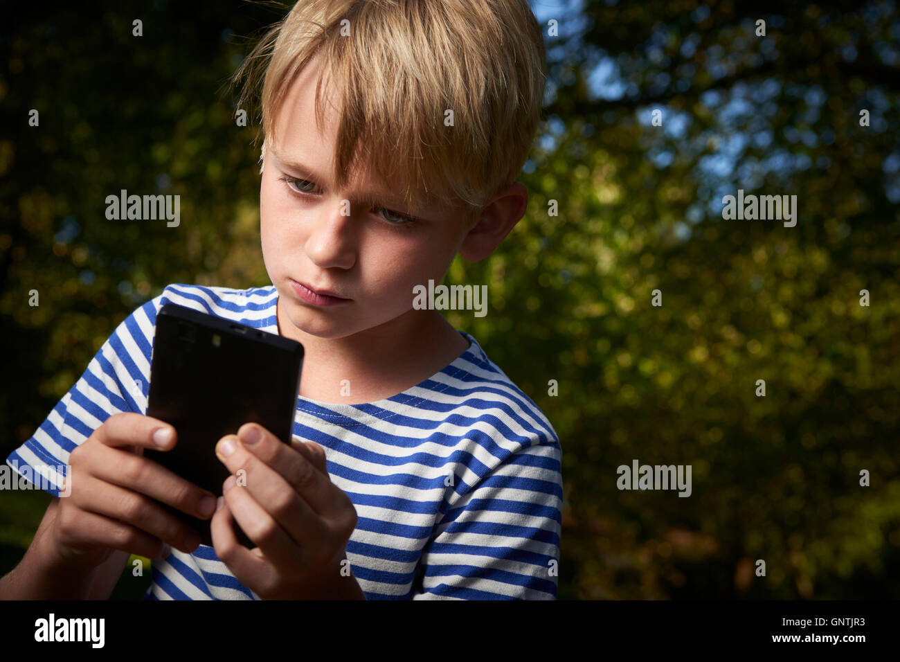 Child young boy with mobile phone outdoor. Child looking at the screen ...