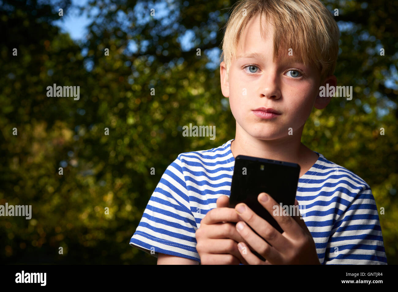 Child young boy with mobile phone outdoor. Child looking at the screen ...