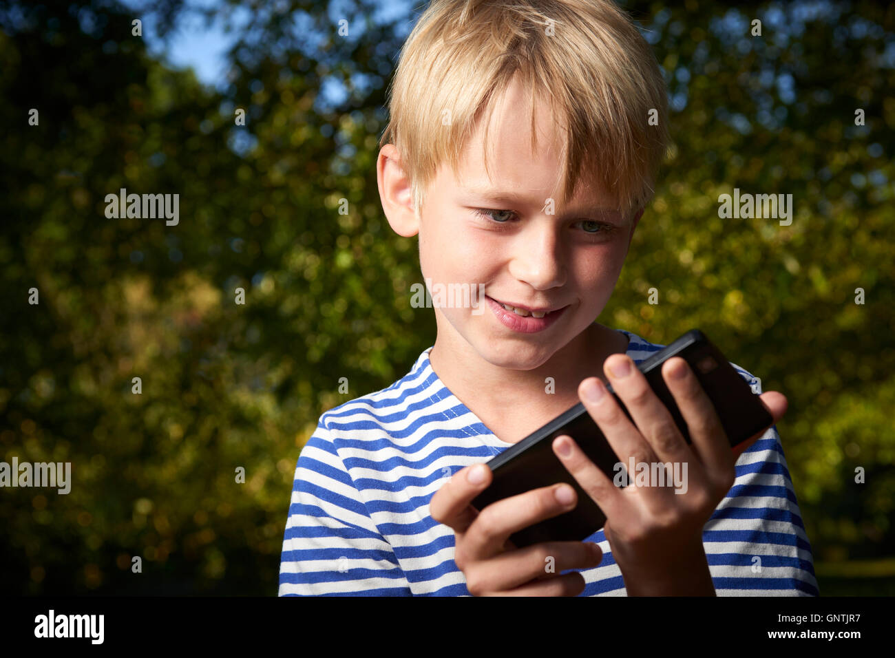 Child young boy with mobile phone outdoor. Child looking at the screen ...
