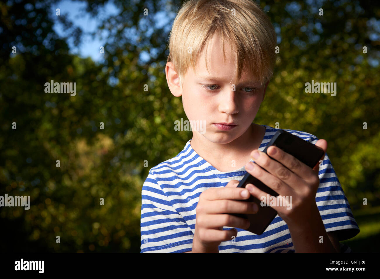 Child young boy with mobile phone outdoor. Child looking at the screen ...