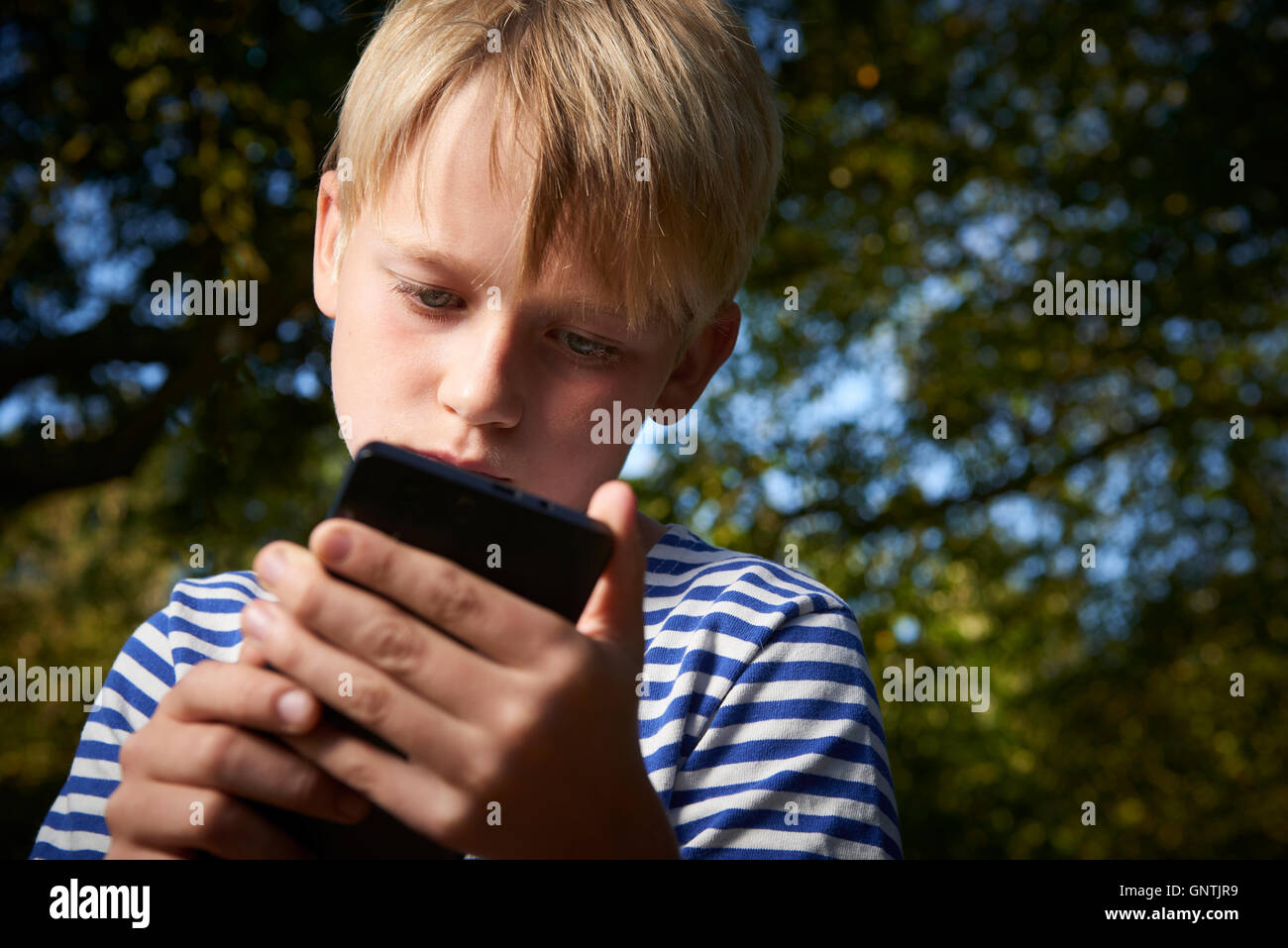 Child young boy with mobile phone outdoor. Child looking at the screen ...