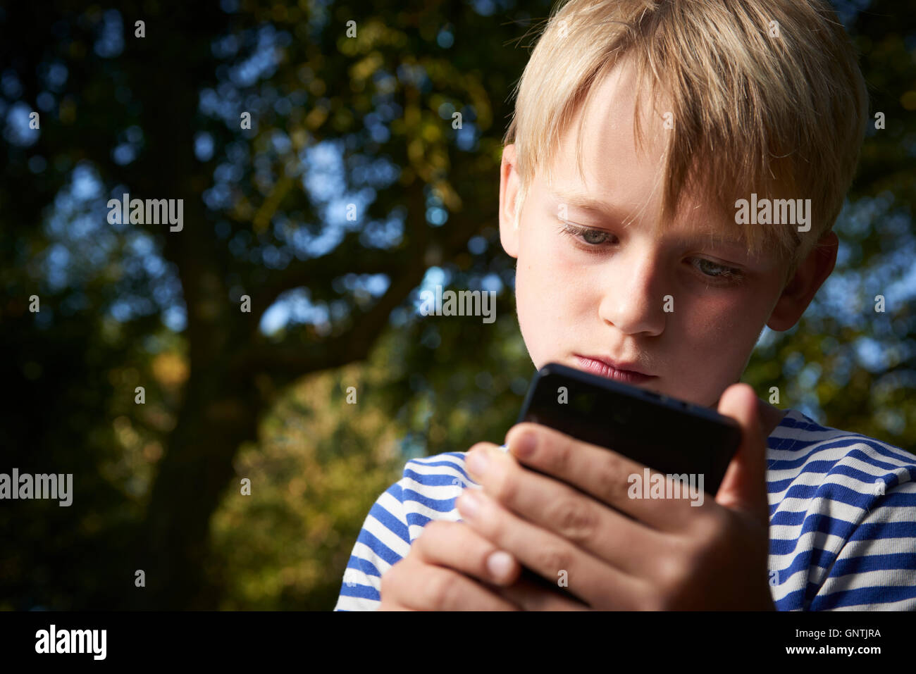 Child young boy with mobile phone outdoor. Child looking at the screen ...