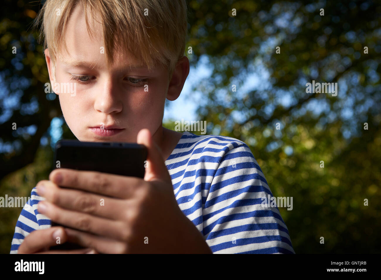 Child young boy with mobile phone outdoor. Child looking at the screen ...