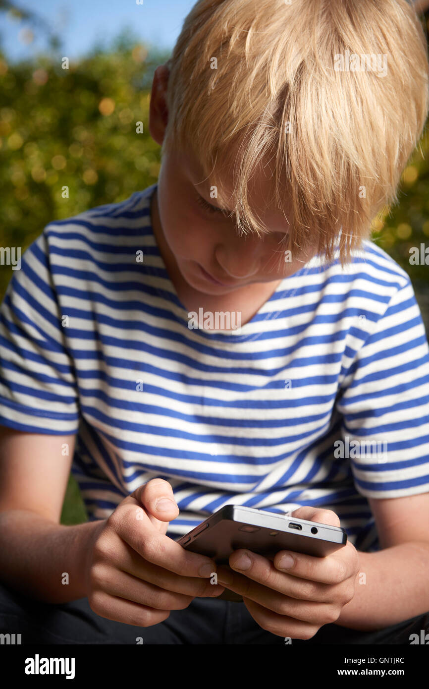 Child young boy with mobile phone outdoor. Child looking at the screen ...