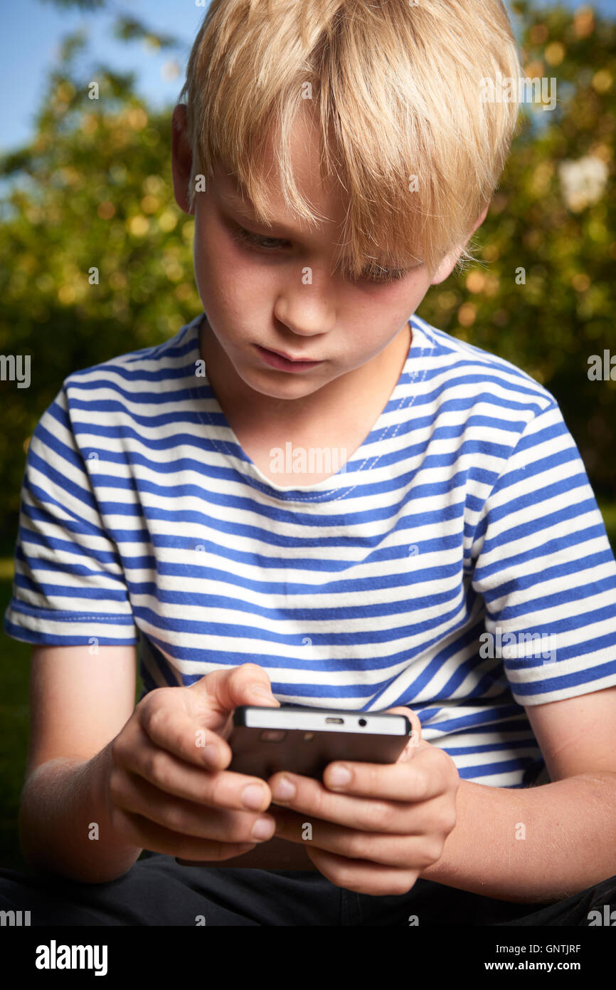 Child young boy with mobile phone outdoor. Child looking at the screen ...