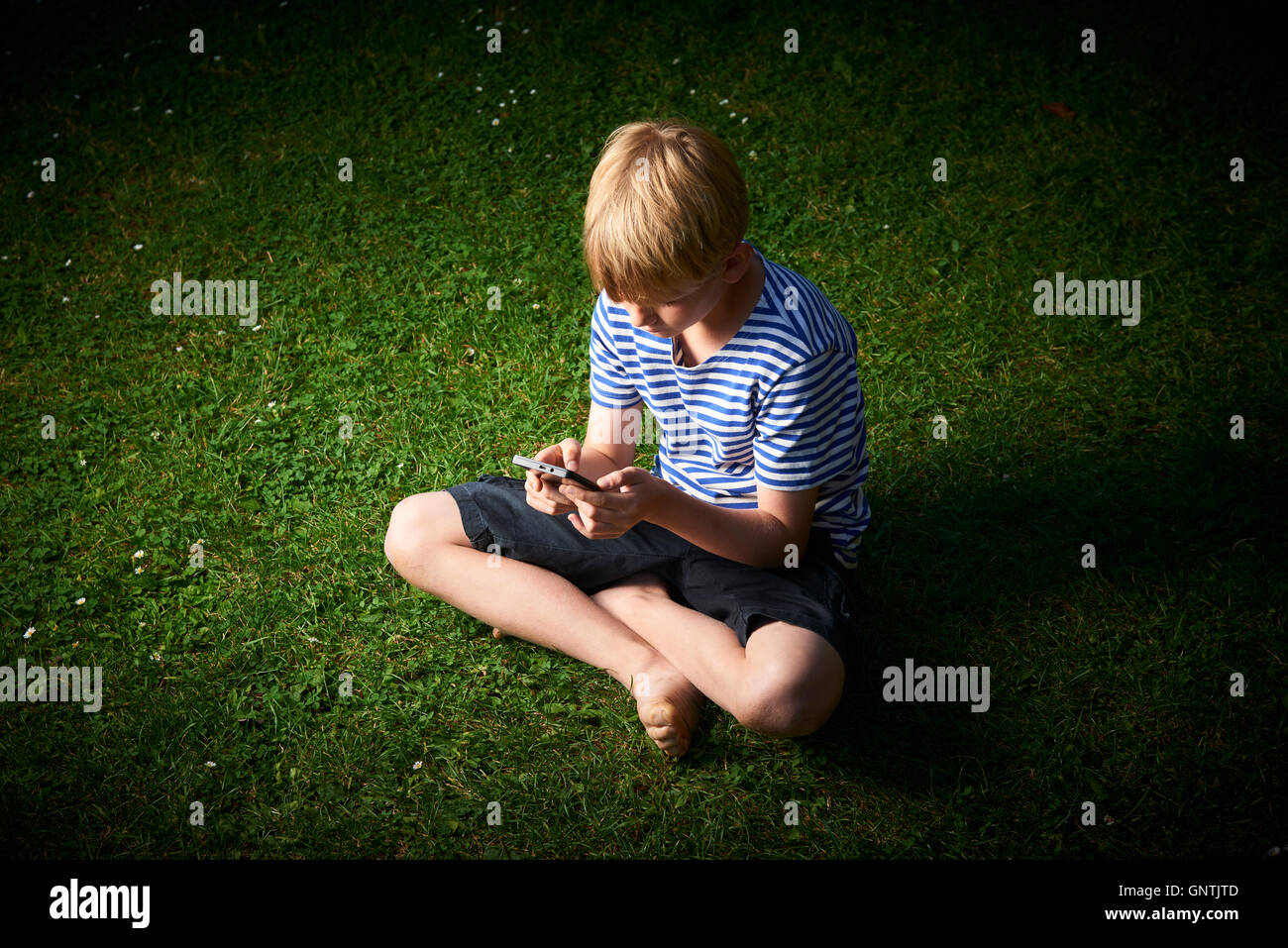 Child young boy with mobile phone outdoor. Child looking at the screen ...