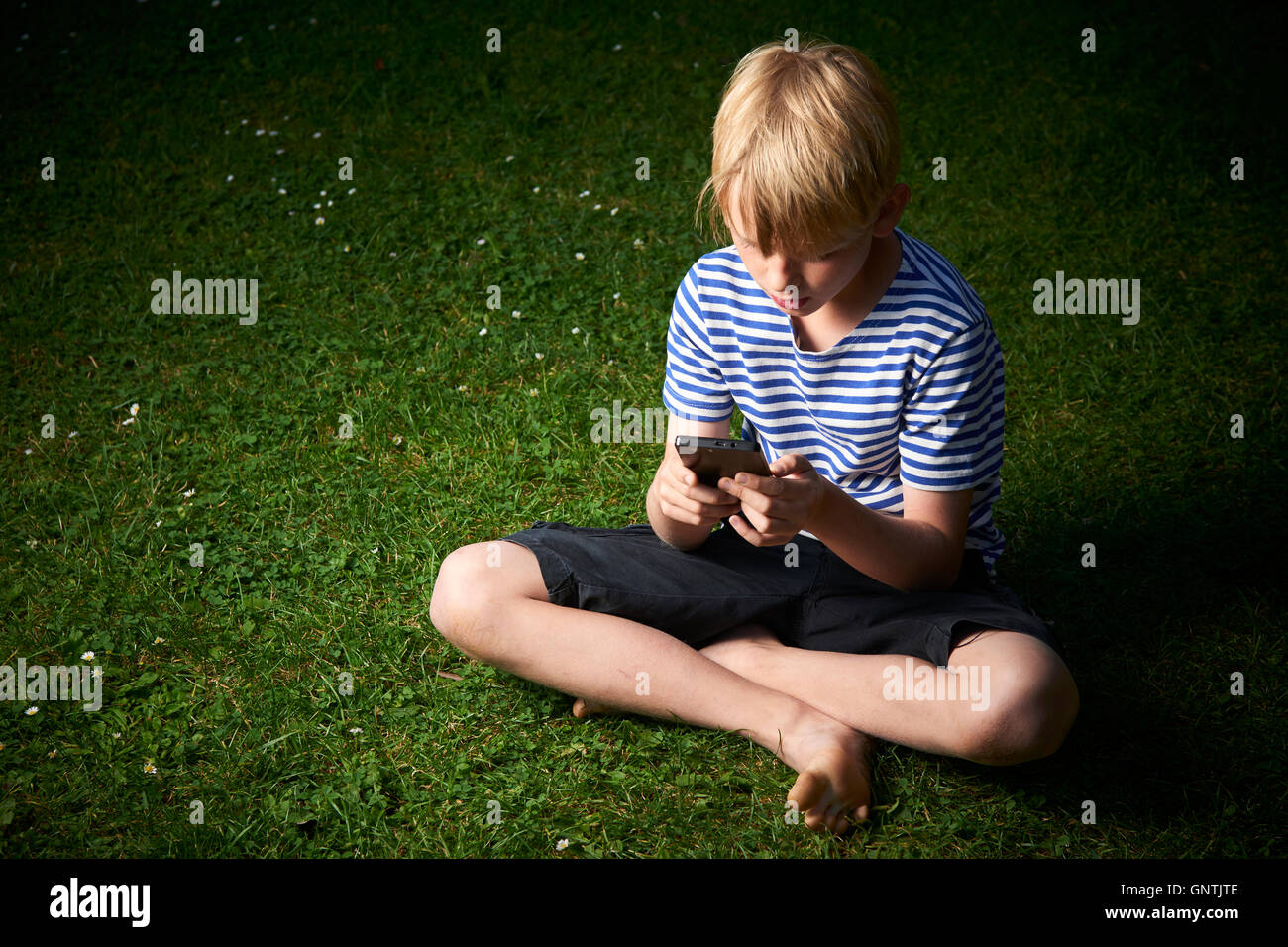 Child young boy with mobile phone outdoor. Child looking at the screen ...