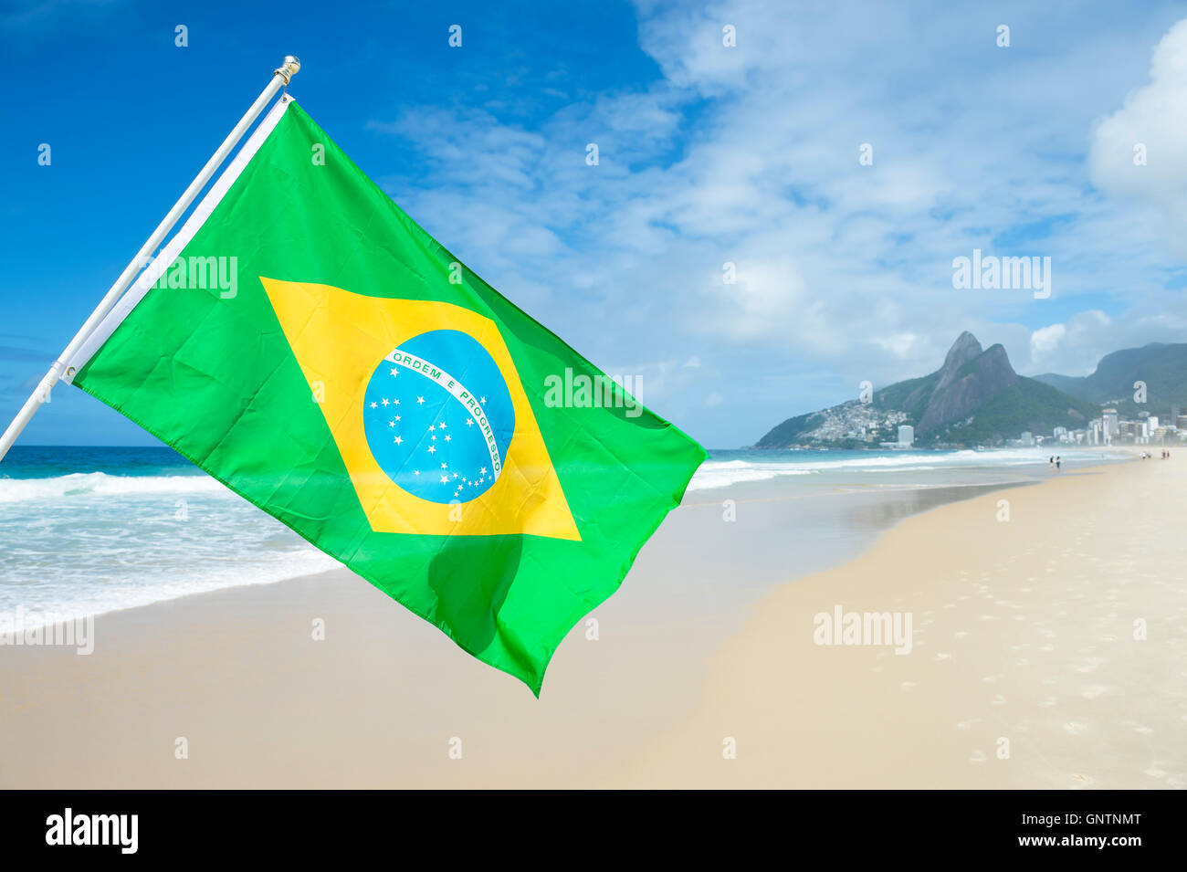 Brazilian flag flying in bright sun above the city skyline at Ipanema ...