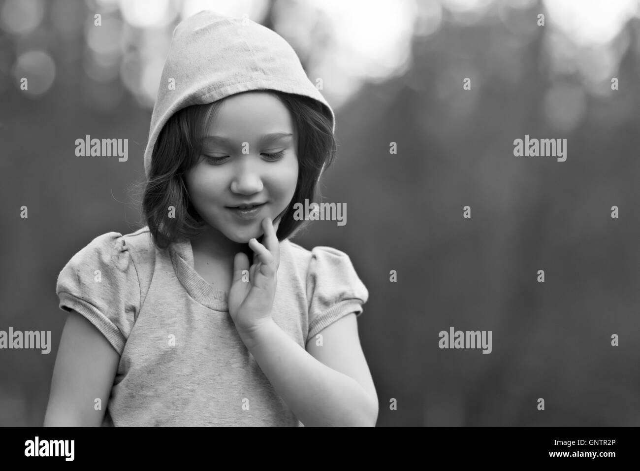 A beautiful young girls looking down solemnly while touching her face ...