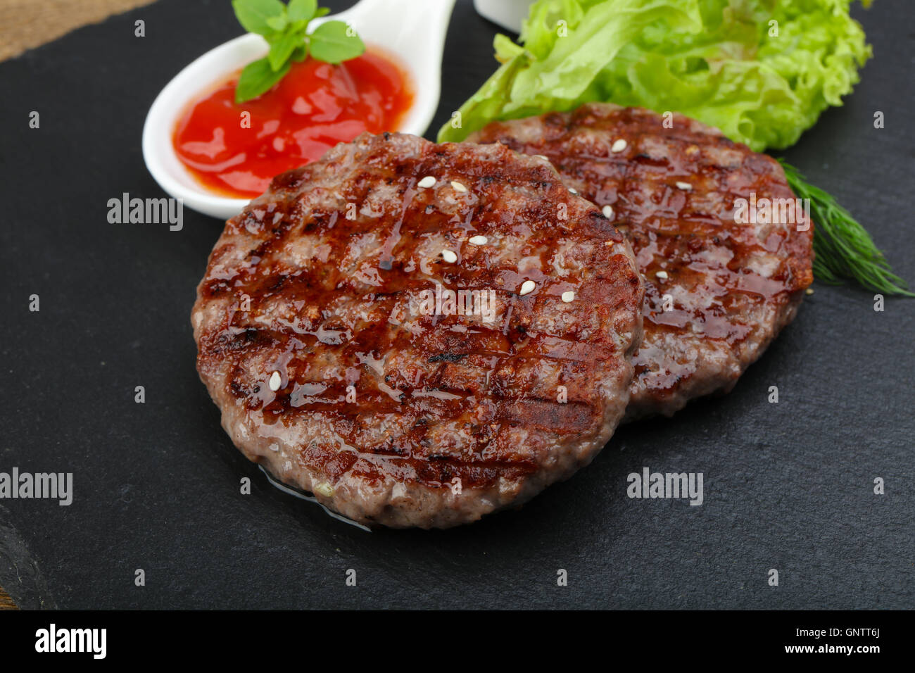 Grilled burger cutlet with onion and salad leaves Stock Photo - Alamy