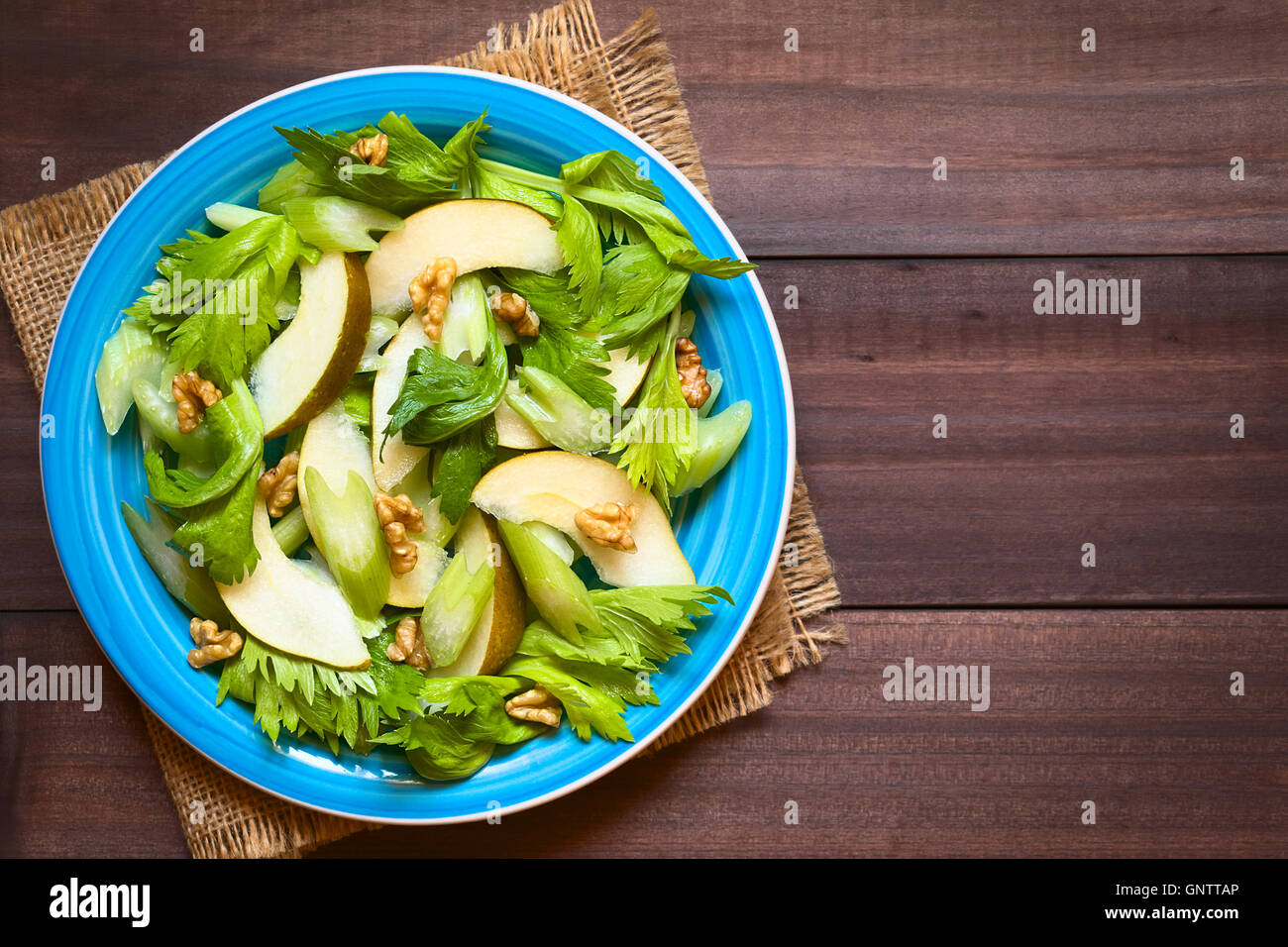 Fresh celery, pear and walnut salad on blue plate, photographed ...