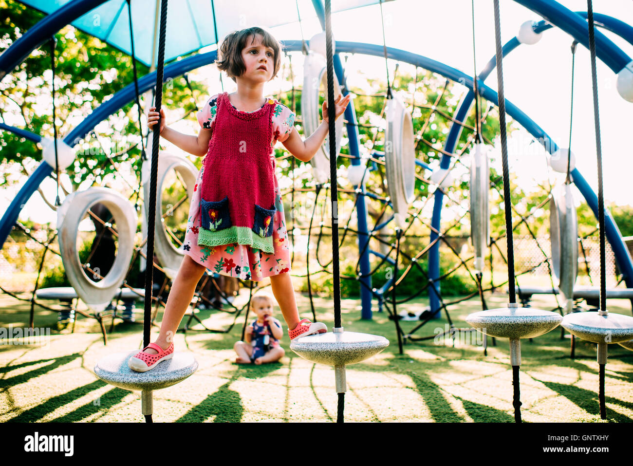 Girl playing on playground in beautiful evening light with baby in the ...