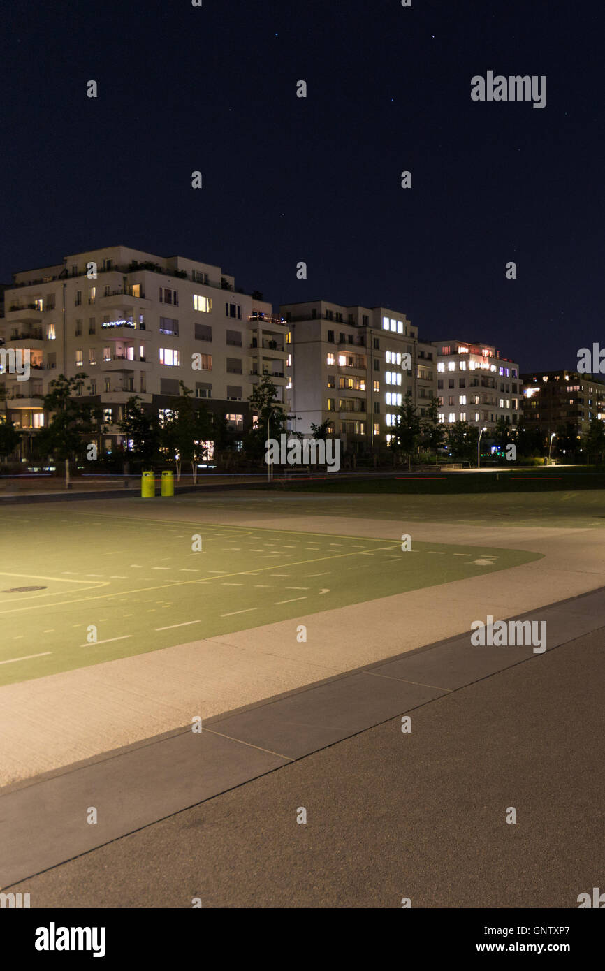 Playground in empty park at night with residential building background ...