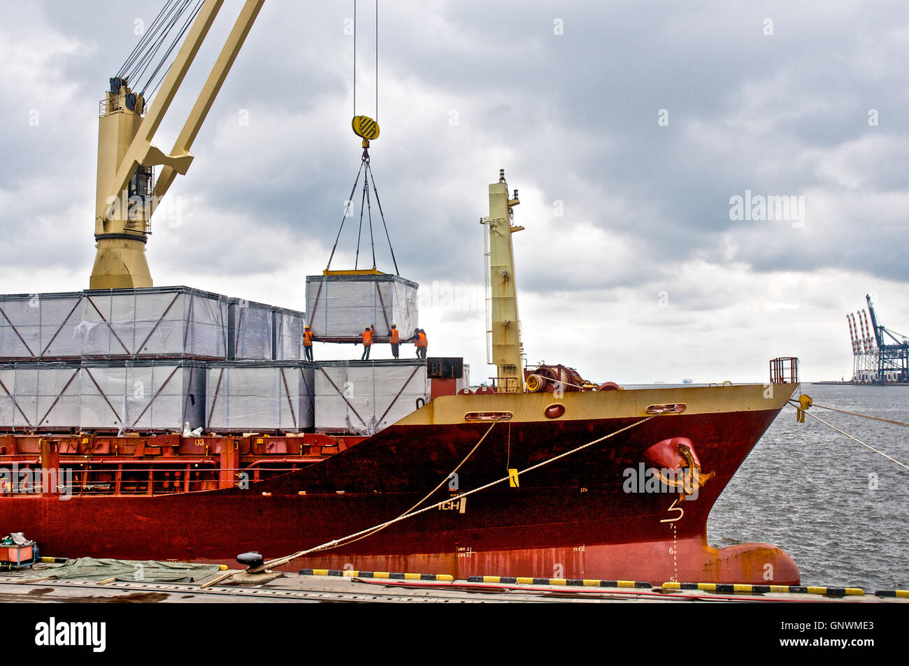 Cargo ship loading cargo into the ship in the harbor Stock Photo - Alamy