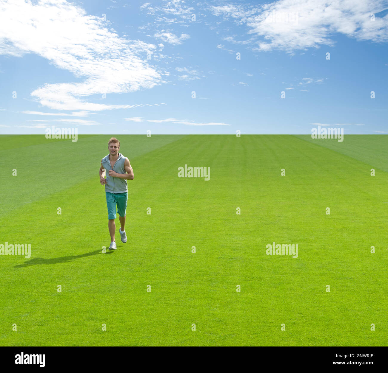 Sporty young man running on green field Stock Photo - Alamy