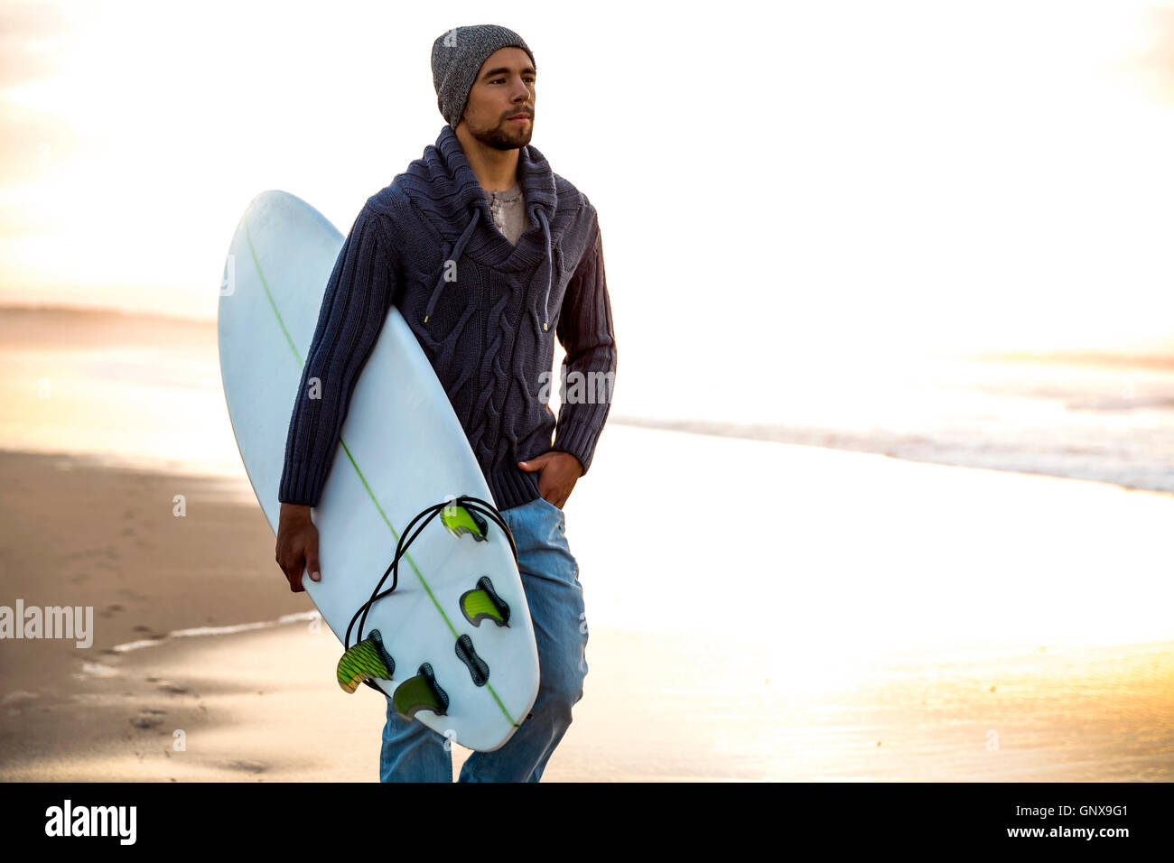 A surfer with his surfboard walking in the beach at the sunset Stock ...