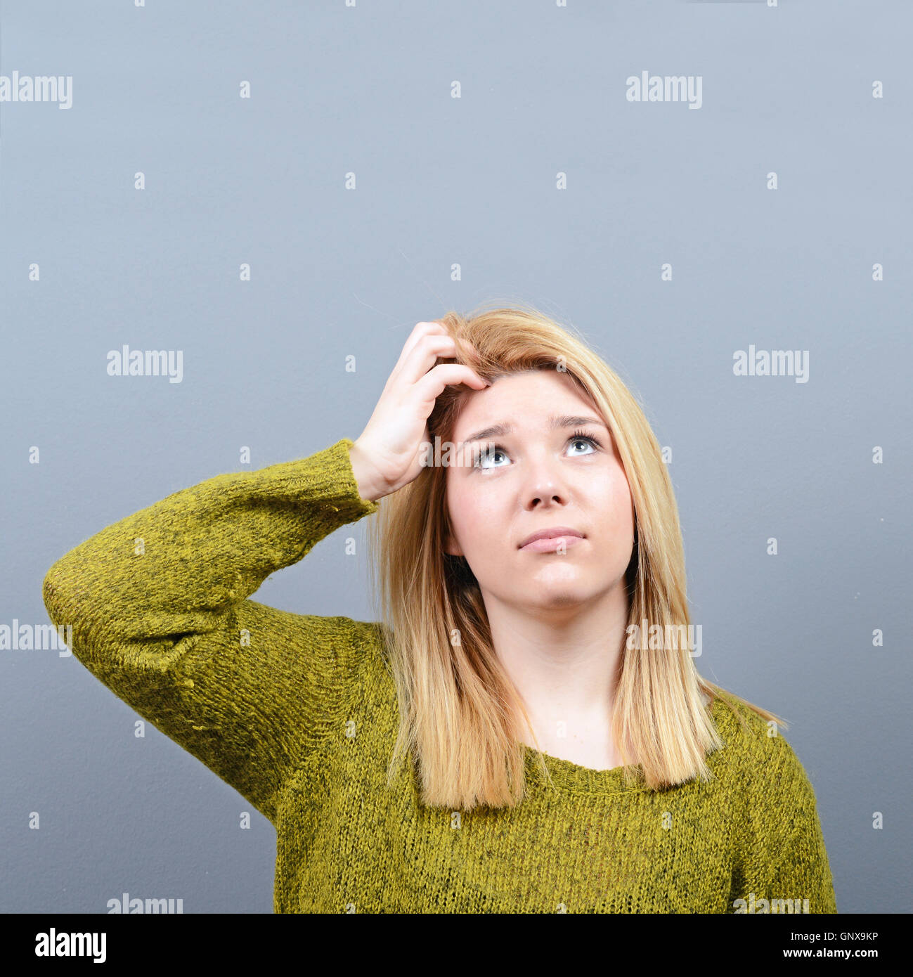 Portrait of forgetful young woman against gray background Stock Photo ...