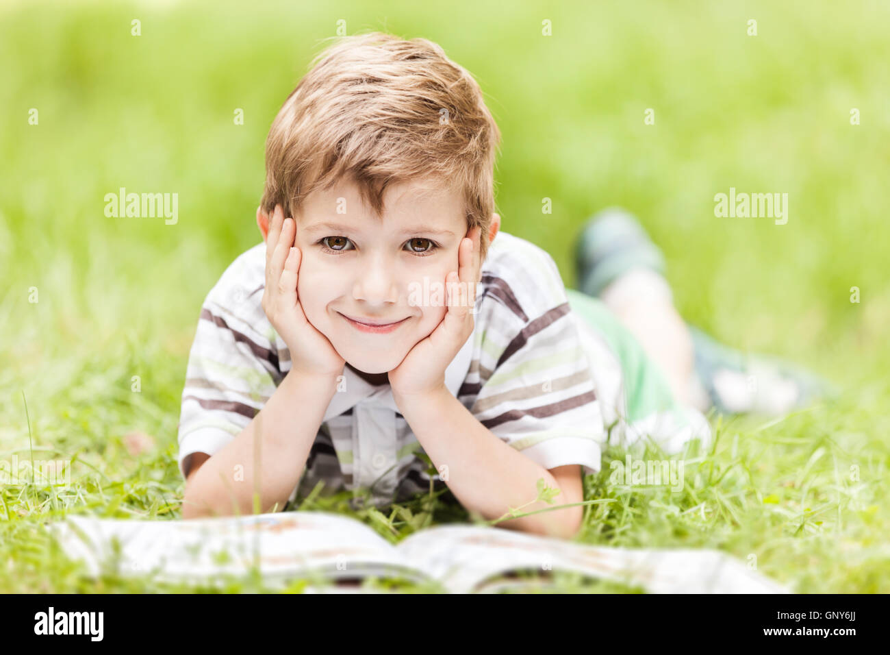 Beauty smiling child boy reading book outdoor Stock Photo - Alamy