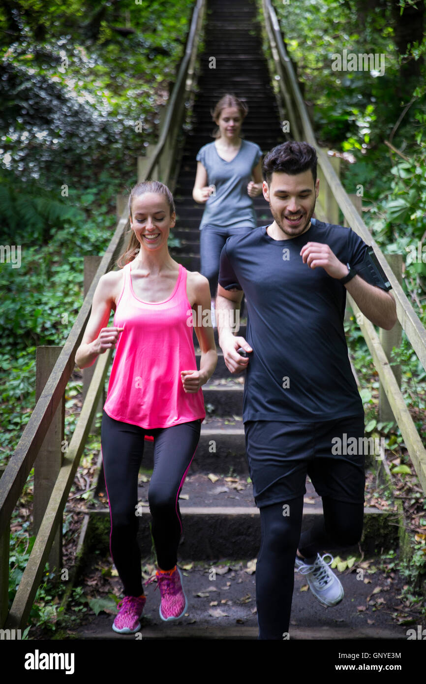 Three friends out running on forest trail, training and exercising ...