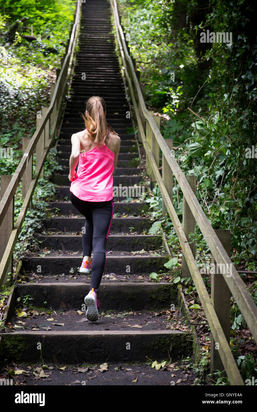 Back view of a fit woman running outdoors up stairs. Action and healthy ...