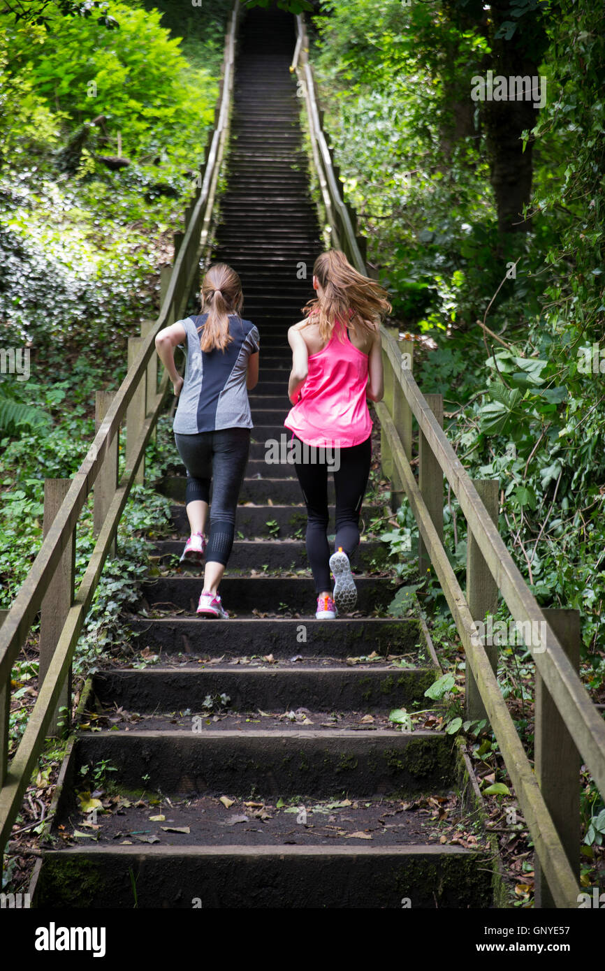 Back view of two women running outdoors up stairs. Action and healthy ...