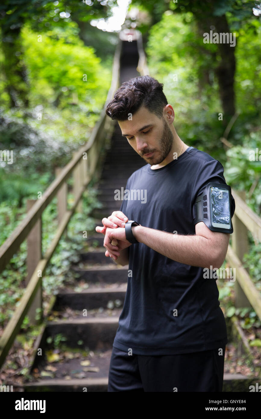 Man out running on forest trail, using his smart watch heart rate ...