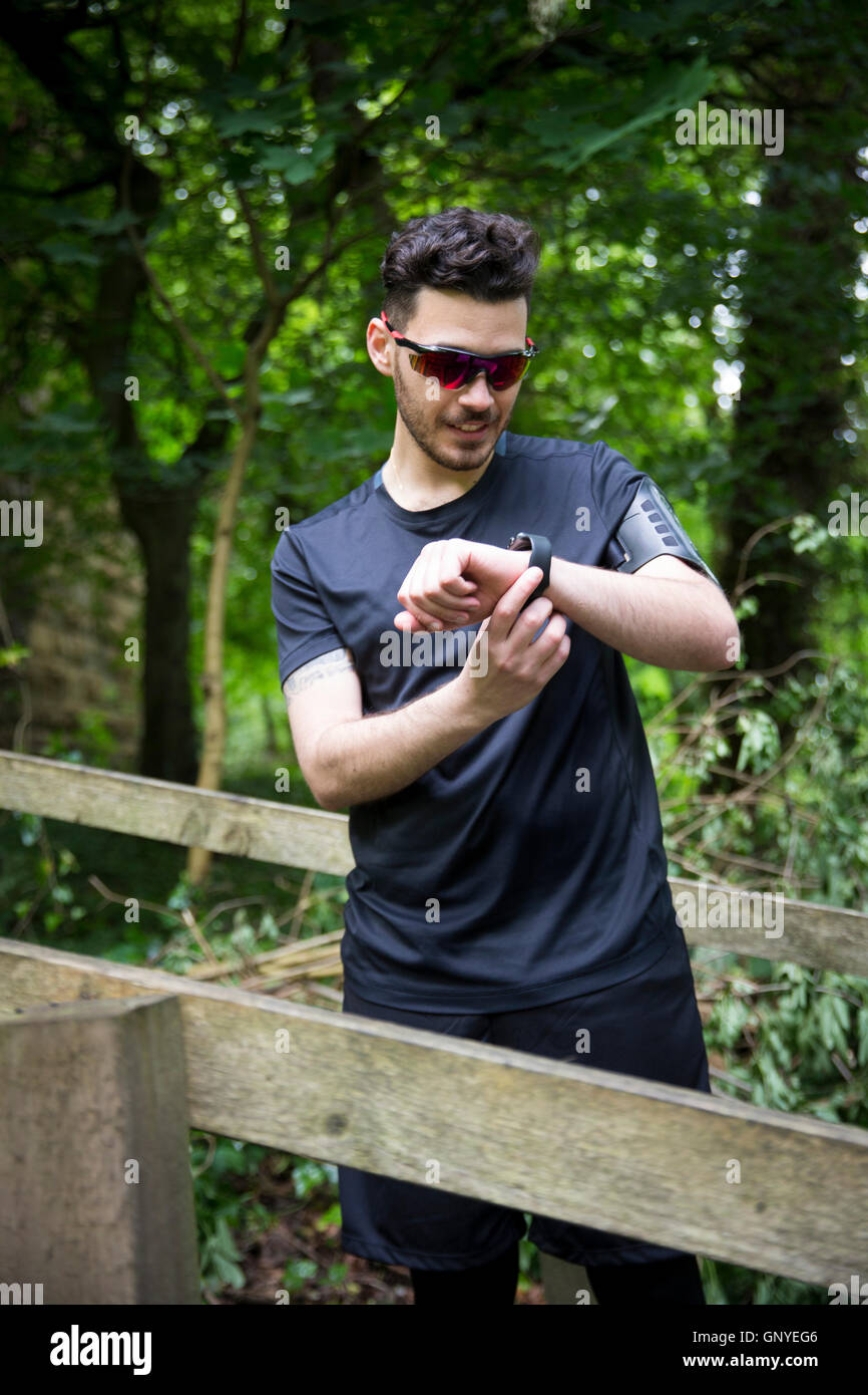 Man out running on forest trail, using his smart watch heart rate ...