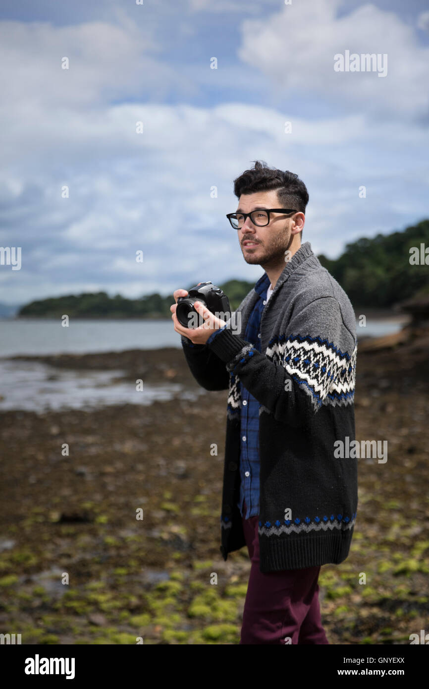 Portrait of man taking landscape photos with a DSLR at the coast ...
