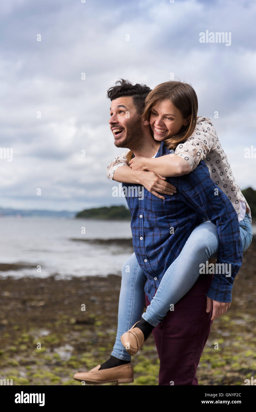 Playful couple hugging while walking along pebble beach. Caucasian ...