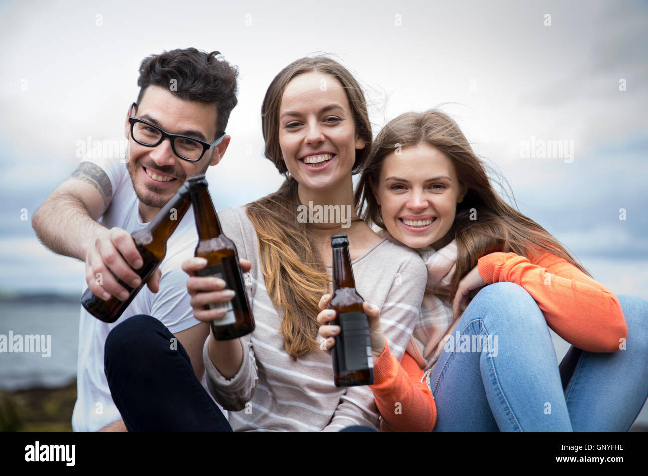 Three Friends toasting with beer bottles outdoors. Caucasian lifestyle ...