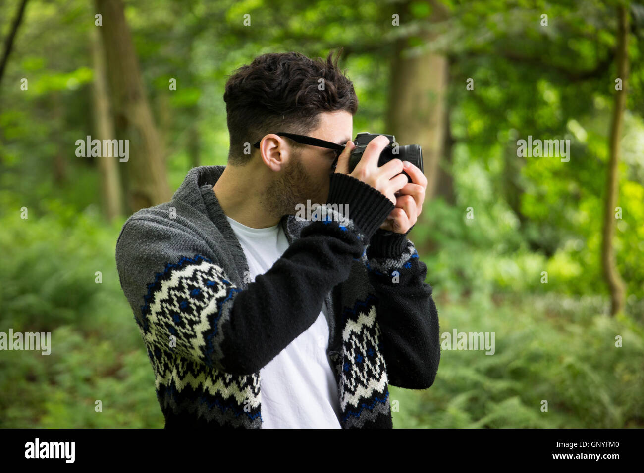 Portrait of man taking landscape photos with a DSLR in a forest ...